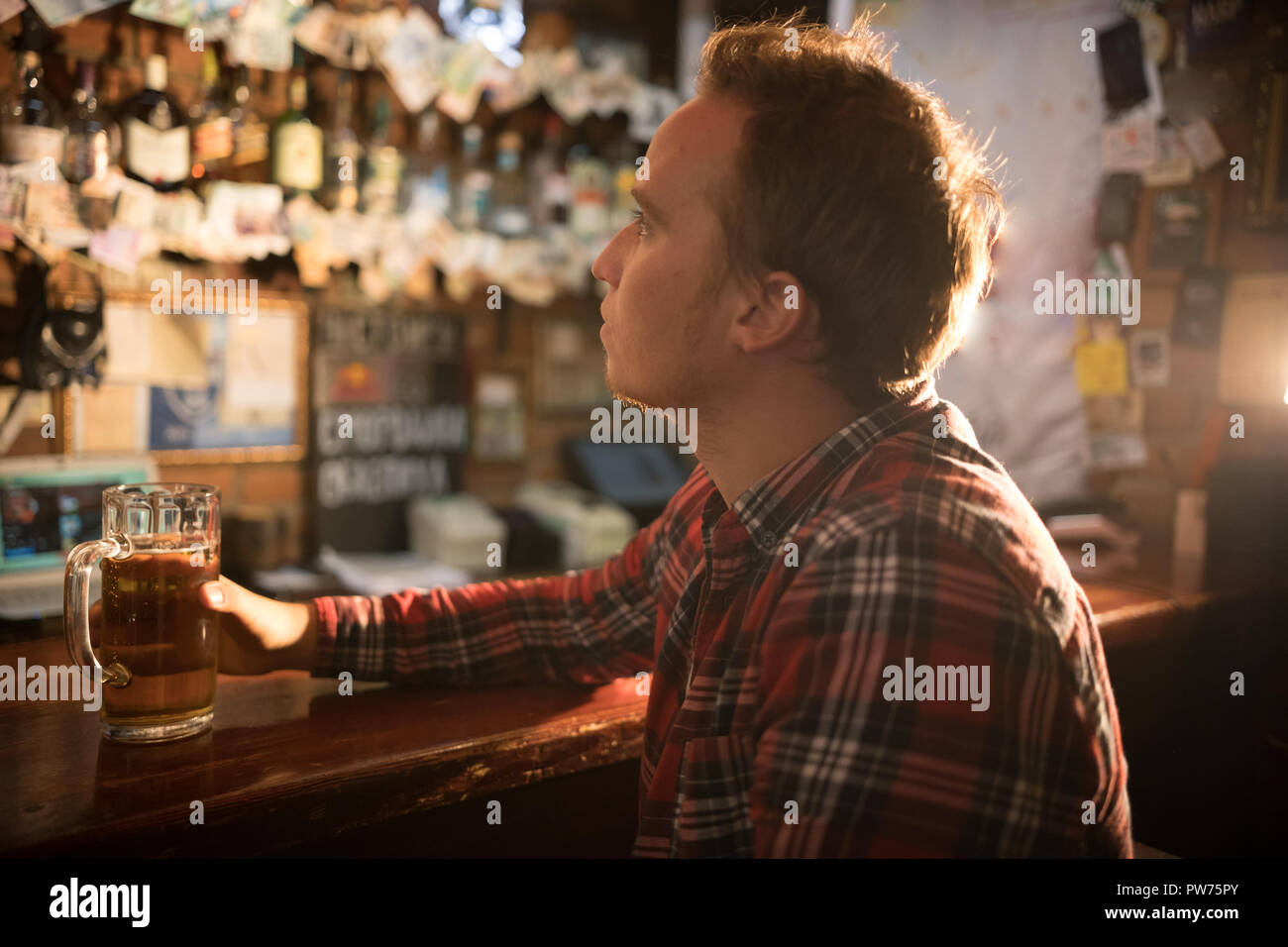 Thoughtful young man drinking beer at the bar in irish pub. Reflecting ...