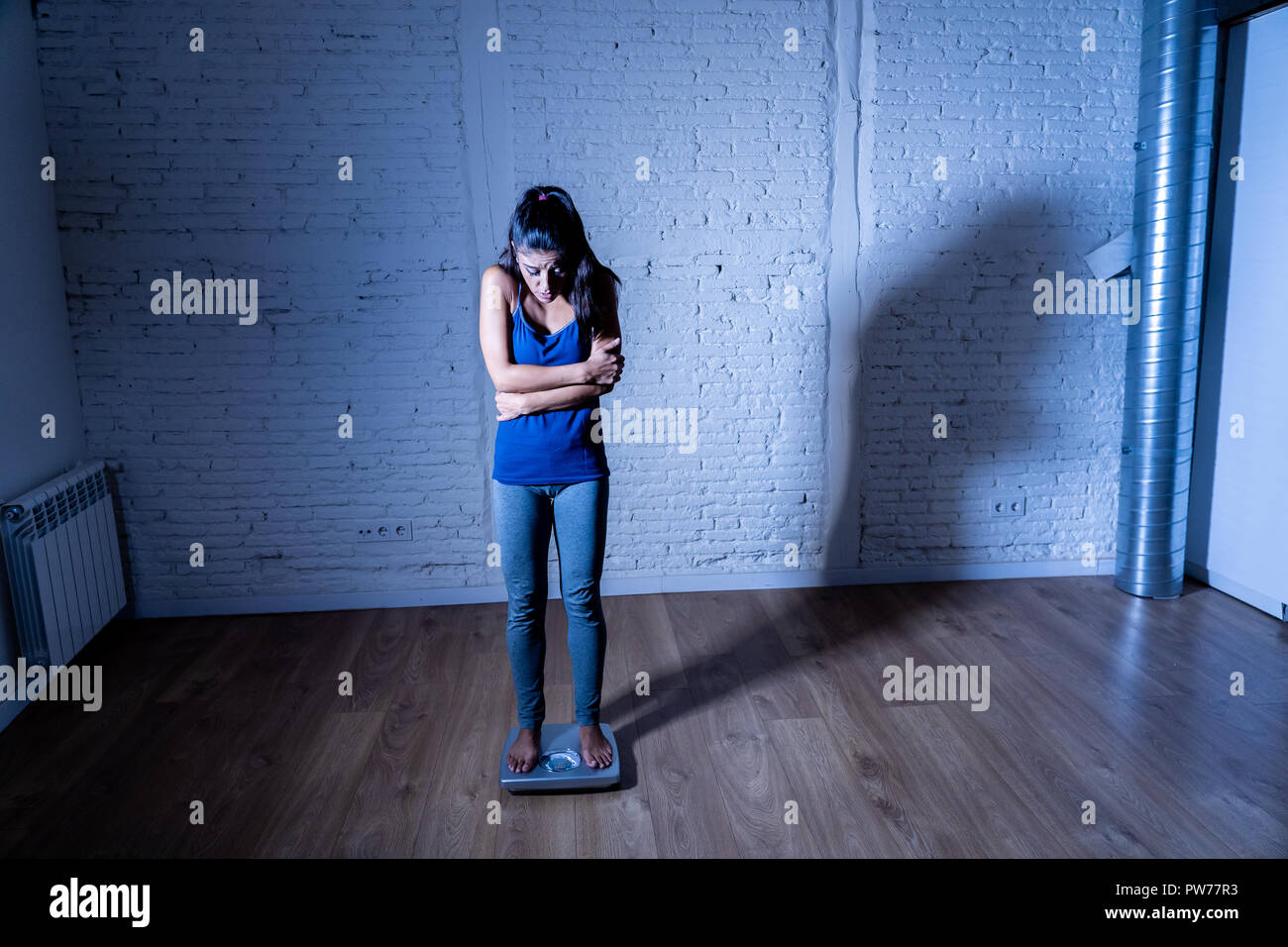 Young fit and slim woman checking body weight on scale finding herself ...