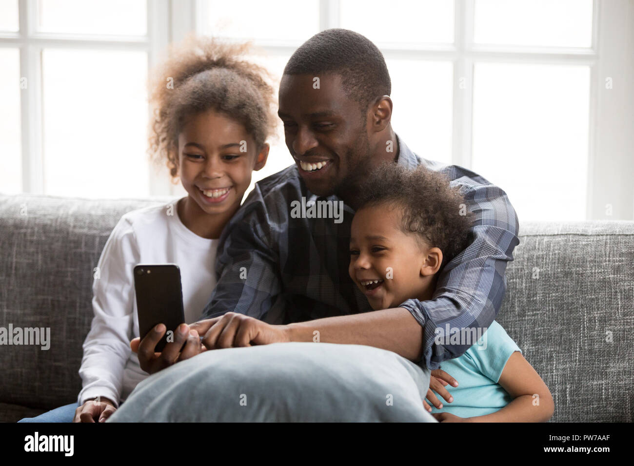 Happy African father with kids using smartphone Stock Photo - Alamy
