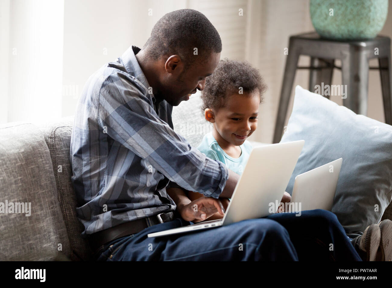 Father with little son using computers sitting on couch Stock Photo - Alamy
