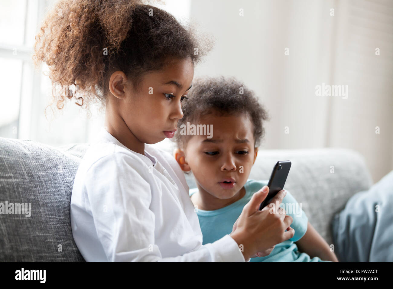 Two black kids with mobile phone indoors Stock Photo - Alamy
