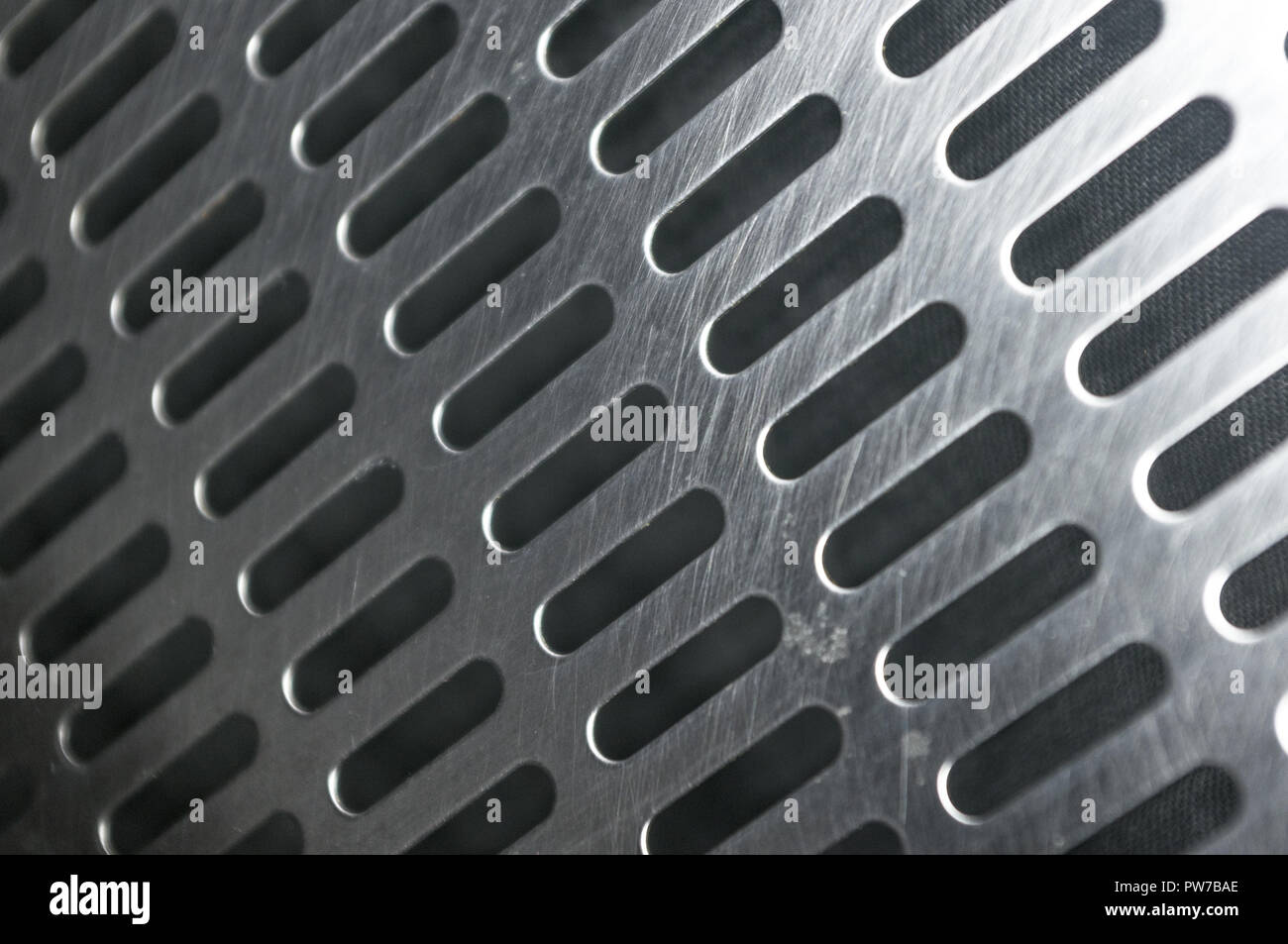 stainless steel grating with oblong holes on black background, close-up ...