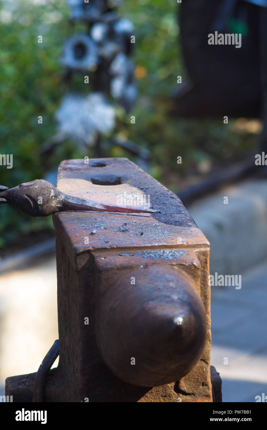 blacksmith performs the forging of hot glowing metal on the anvil ...