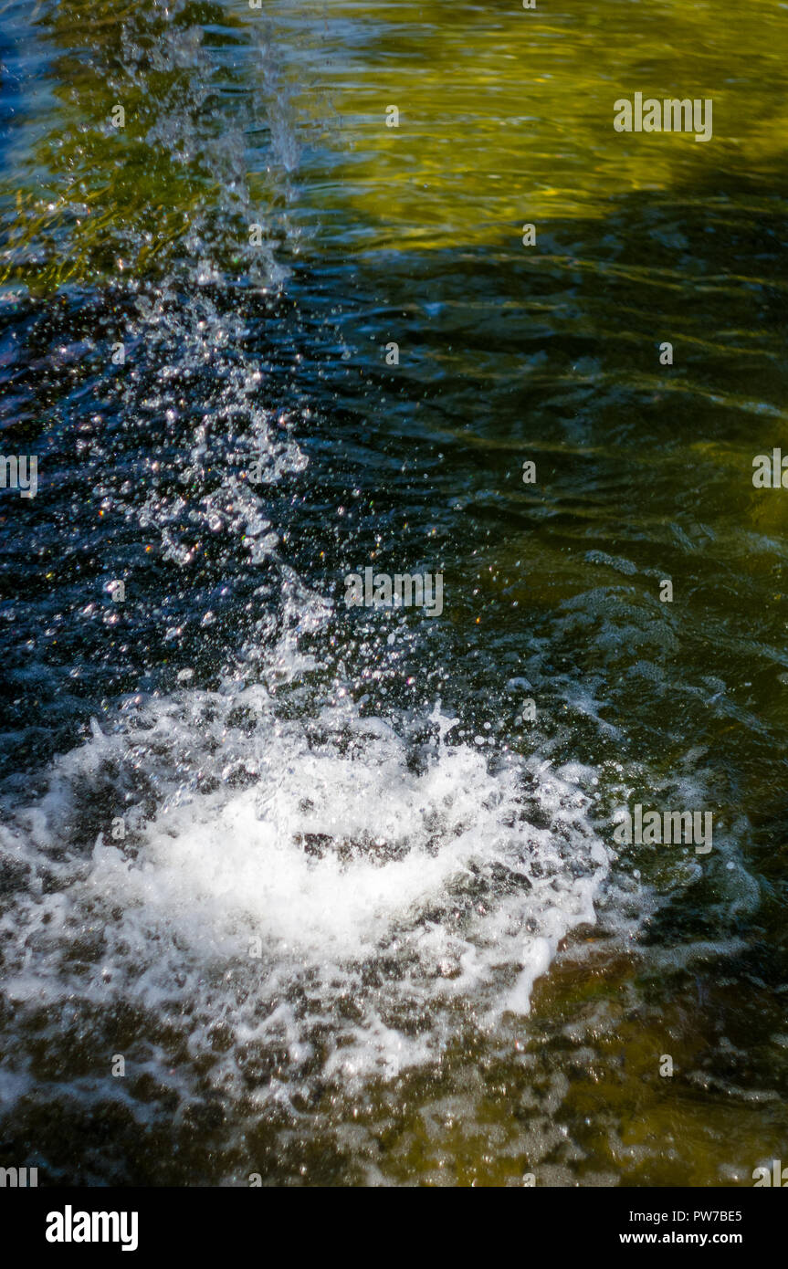 transparent falling water vertical flows against a blue sky and green ...