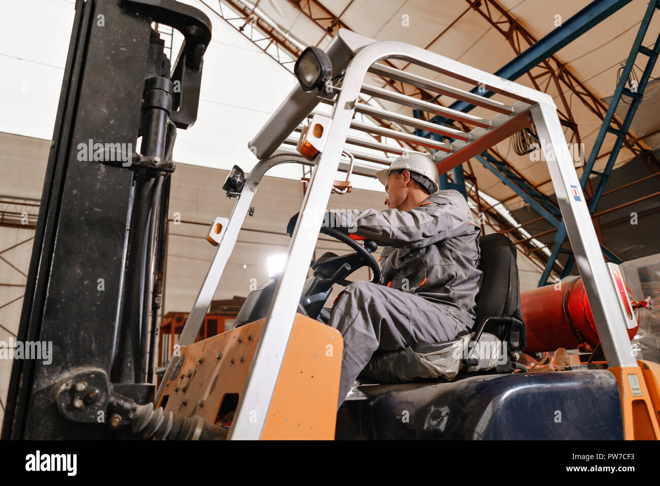 man driving a forklift through a warehouse in a factory. driver in ...
