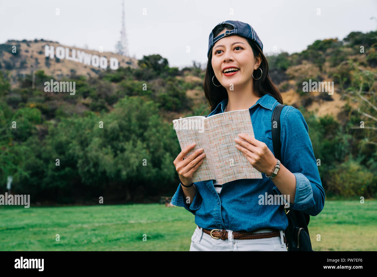 elegant female tourist holding her guidebook and joyfully seeing the ...