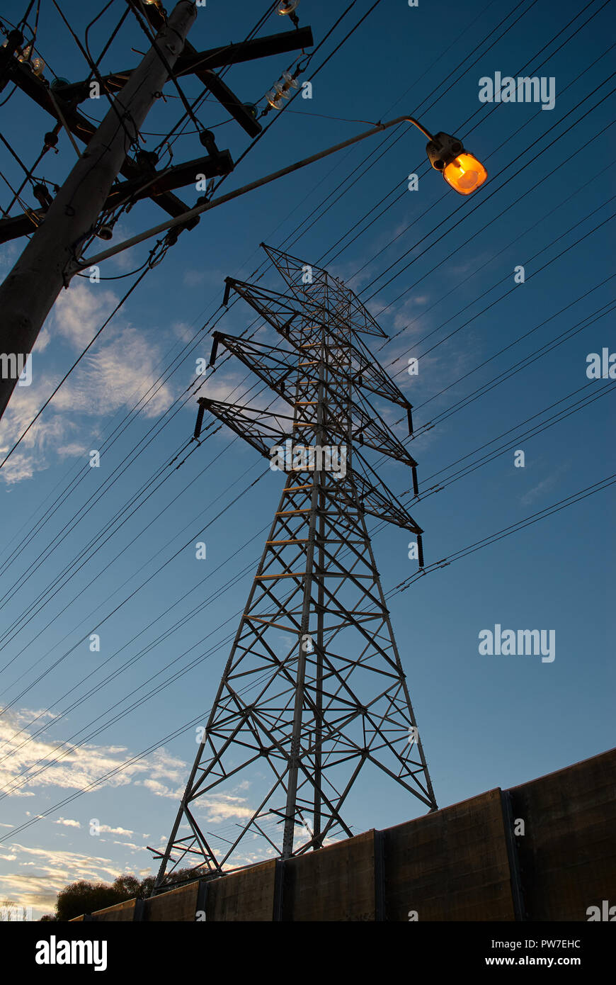 Electric power supply pole and a pylon street light against a bright ...
