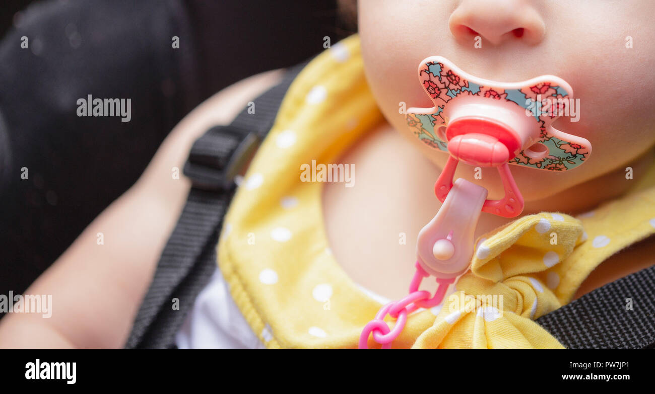 Toddler girl in a yellow outfit with a pink pacifier Stock Photo - Alamy