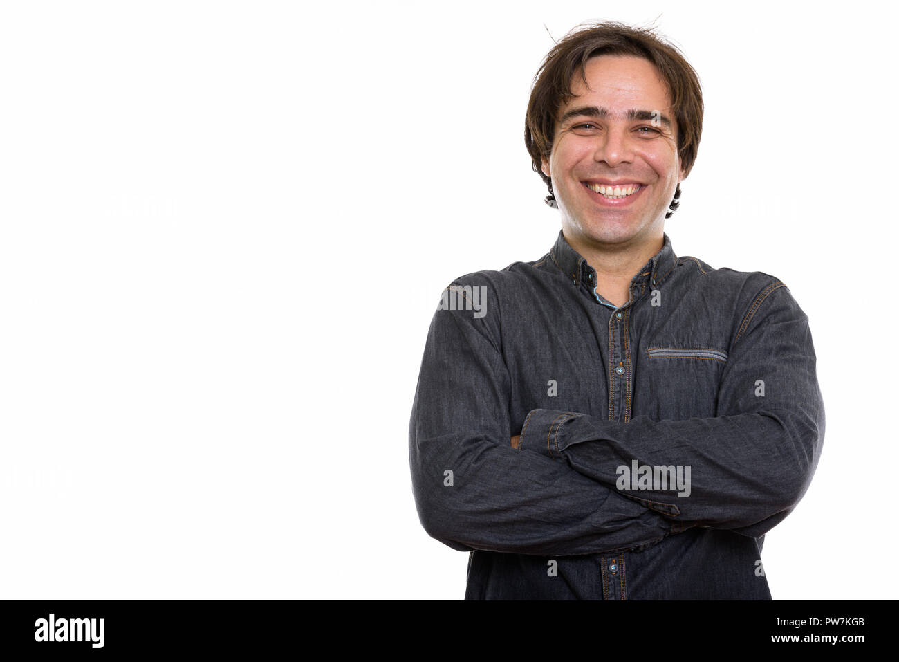 Studio shot of young happy Persian man smiling with arms crossed Stock ...