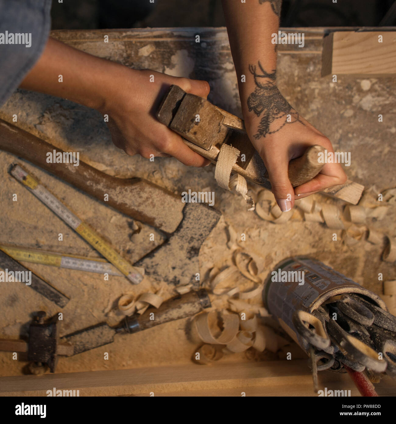 Handmade concept. Female hands with a tattoo make a wooden product ...
