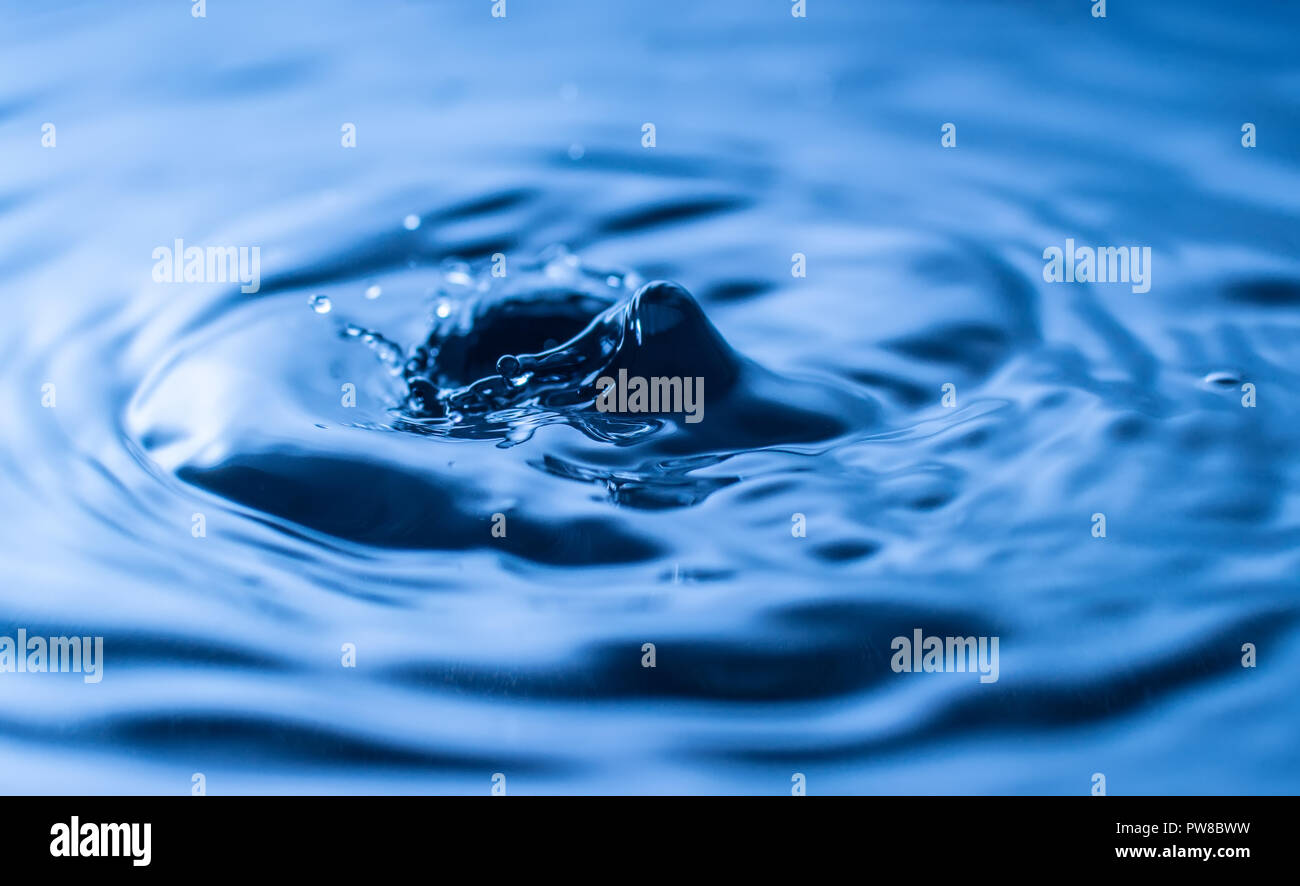 water drop splash in a glass blue colored Stock Photo - Alamy