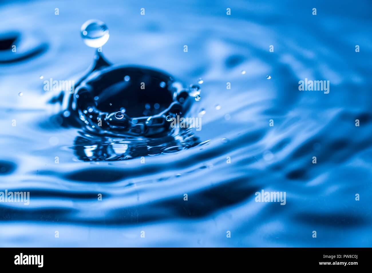water drop splash in a glass blue colored Stock Photo - Alamy