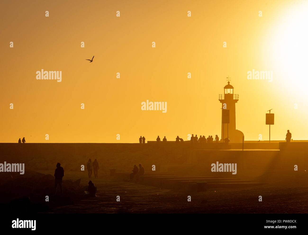 A group of people stand near a lighthouse before sunset Stock Photo - Alamy