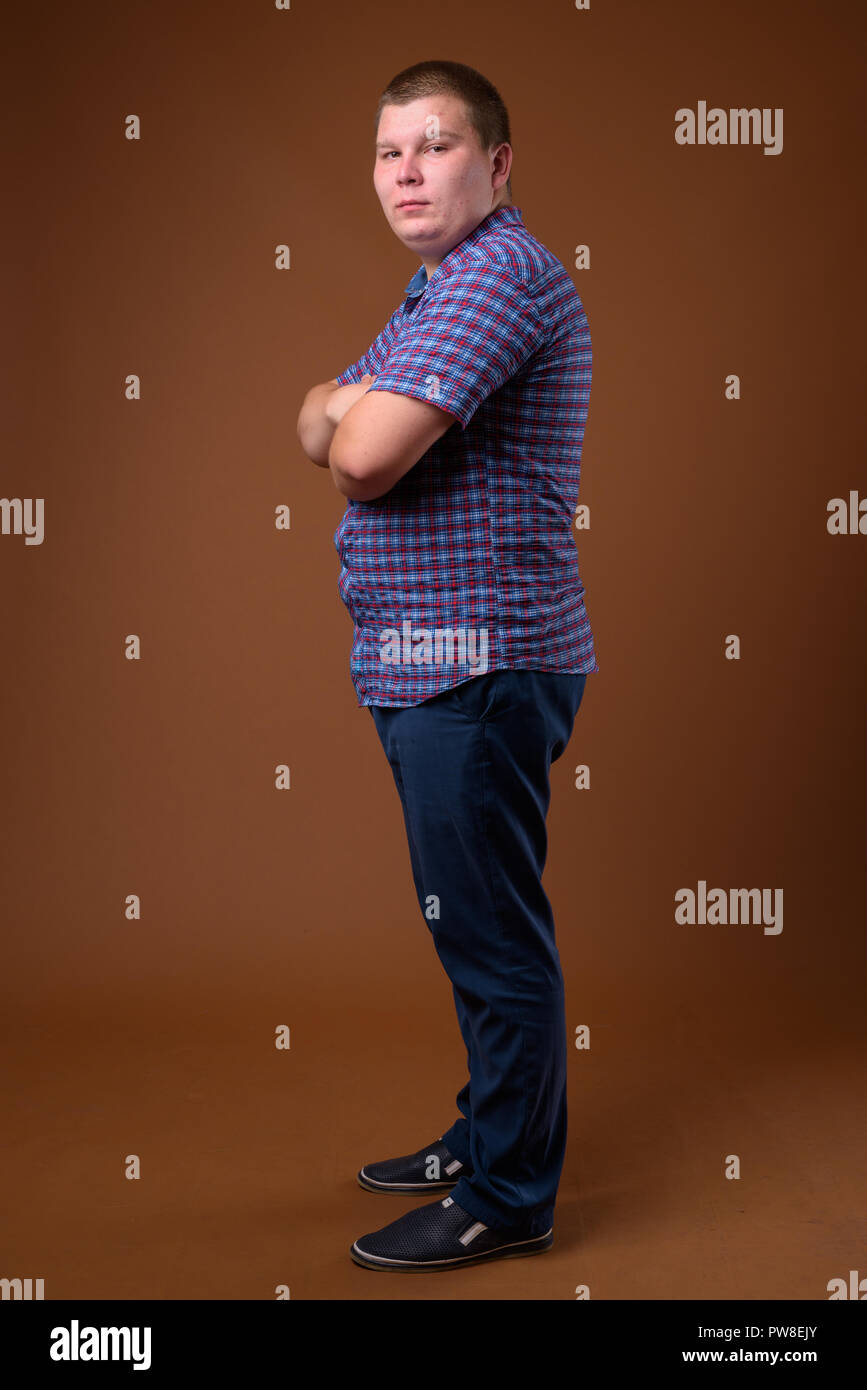 Studio shot of overweight young man against brown background Stock ...
