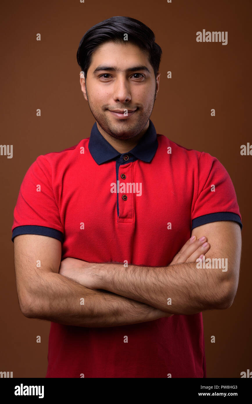 Studio shot of young handsome Iranian man against brown backgrou Stock ...