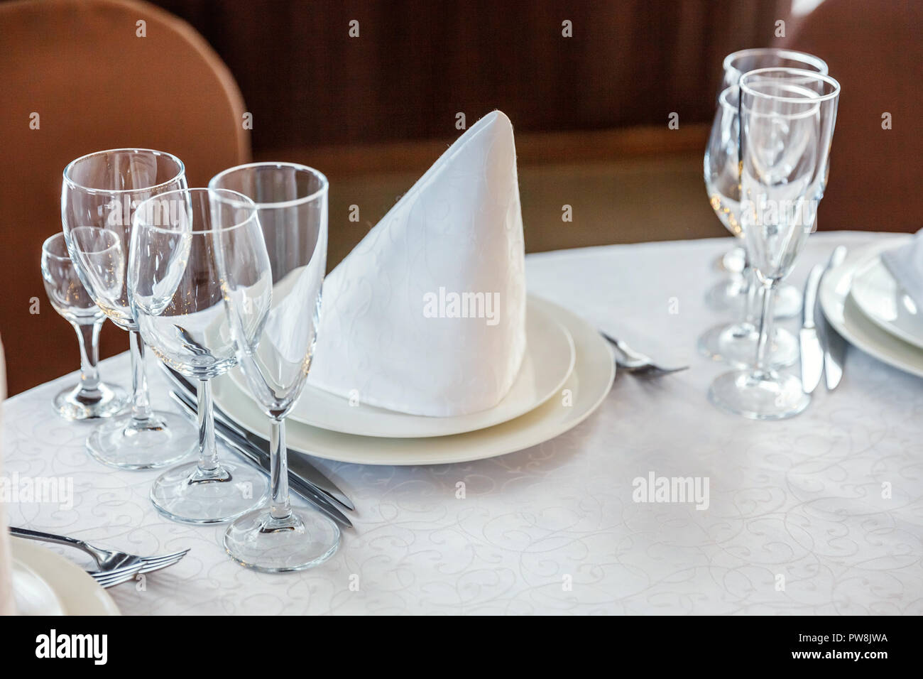 Glasses, flowers, fork, knife, napkin folded in a pyramid, served for ...
