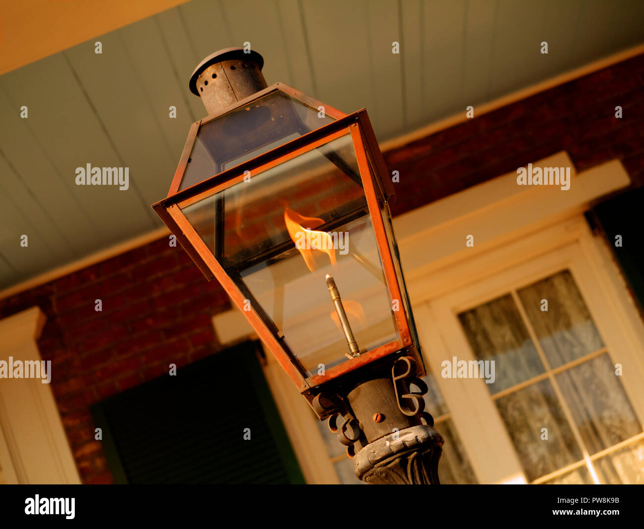 Antique gas lamp with burning flame in early evening with house in ...