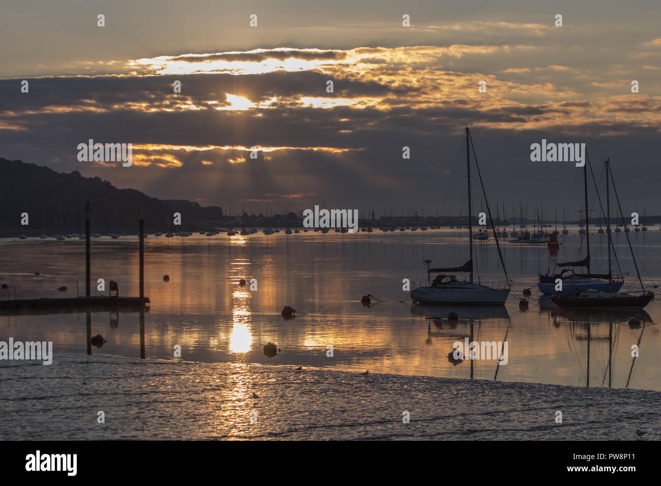 Ships rest at berth on the River Medway at Upnor, Kent as the sun rises ...