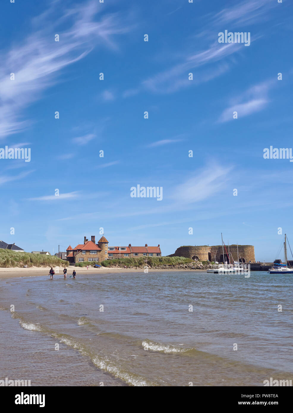 People paddling in the Sea at Beadnell bay in Northumberland close to ...