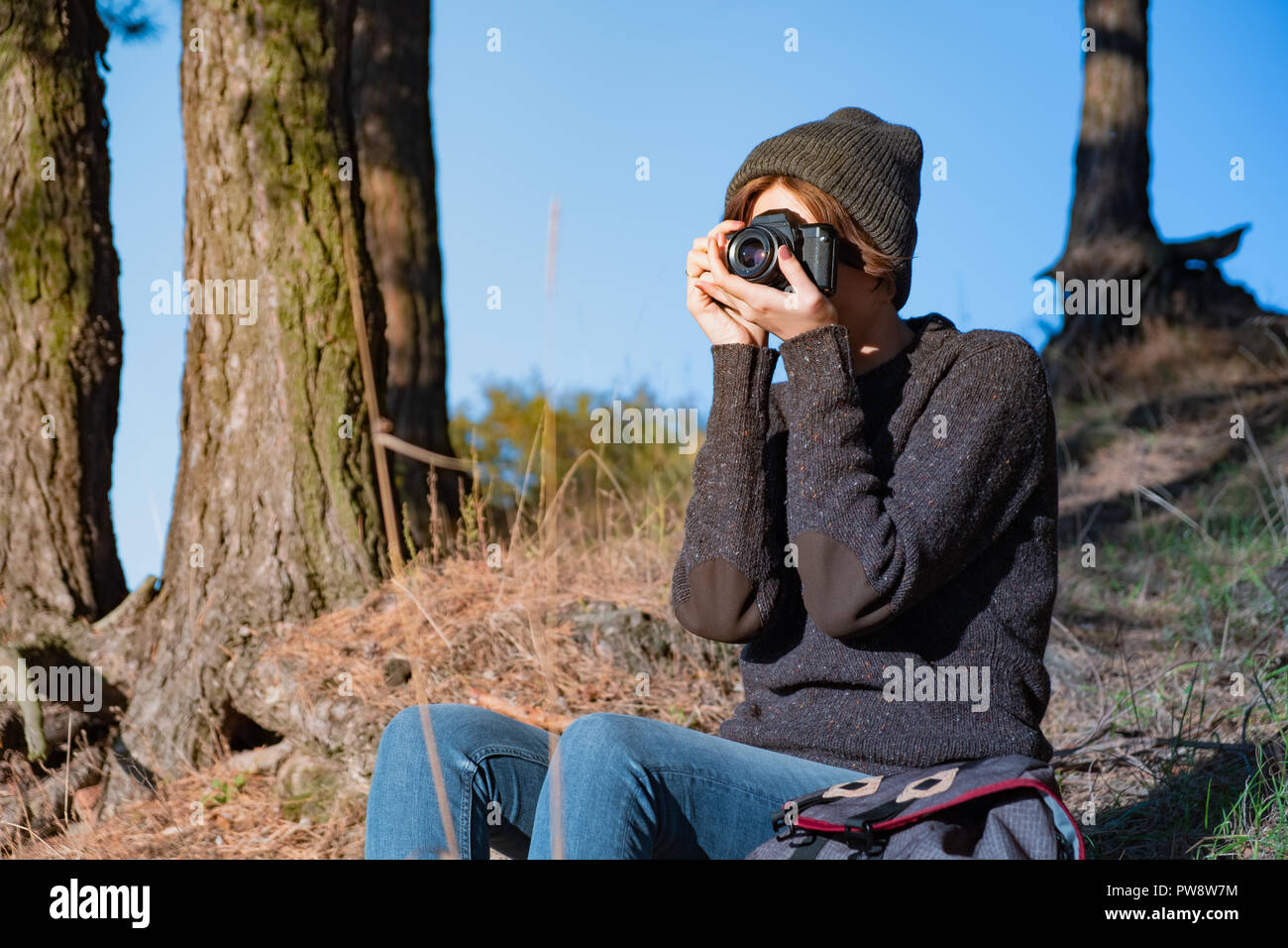 Taking a photo with an old analog camera in the forest. Female hiker ...
