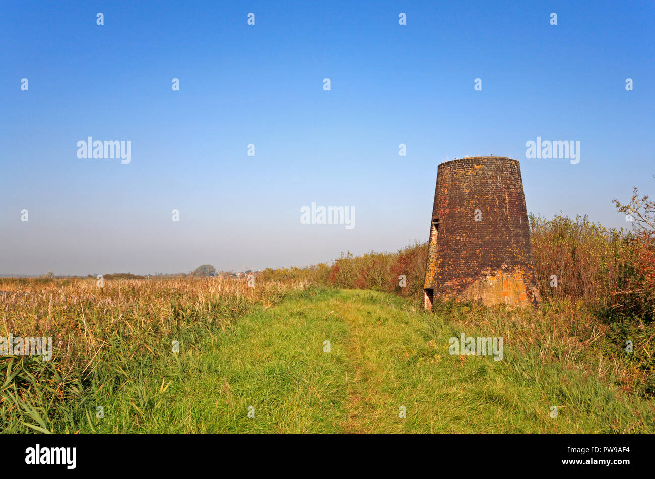 A footpath and flood wall past a derelict drainage mill and the River ...