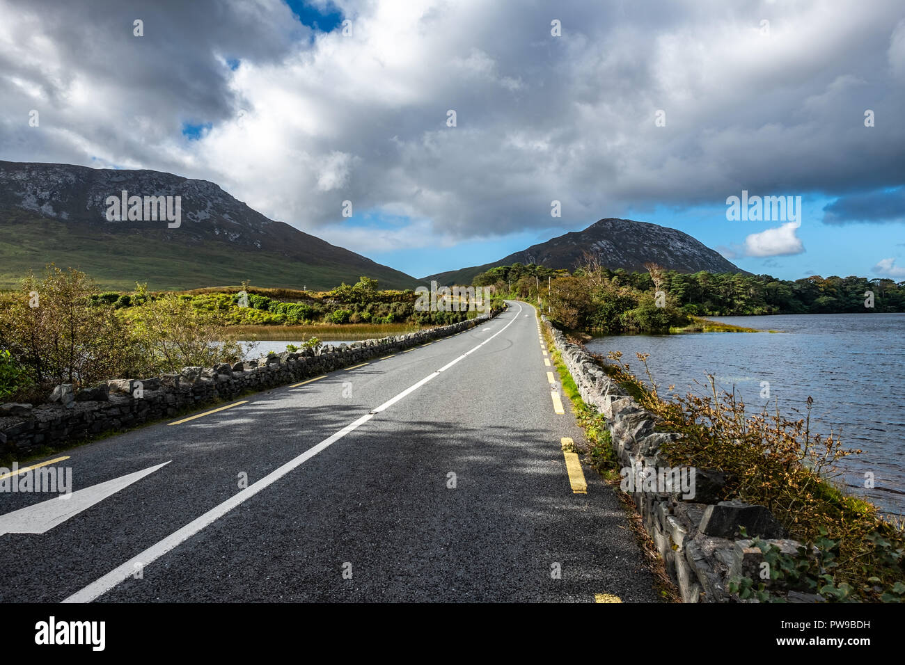 Road alongside a lake with hills in background County Galway, Ireland ...