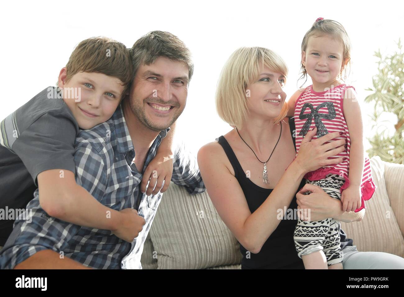 Happy family of four sitting on sofa Stock Photo - Alamy