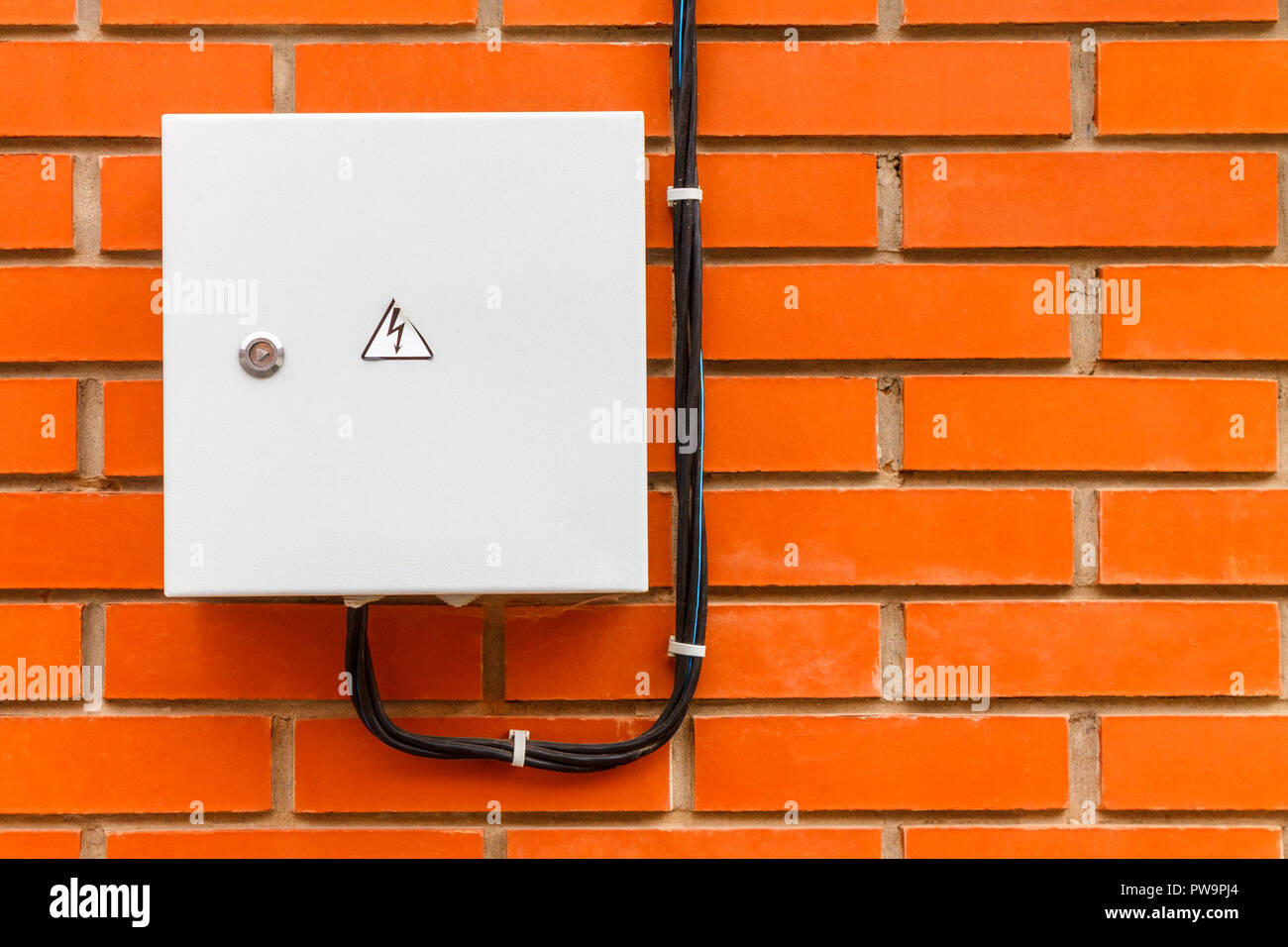 Electrical box with cable and danger sign on a red brick wall. Image ...