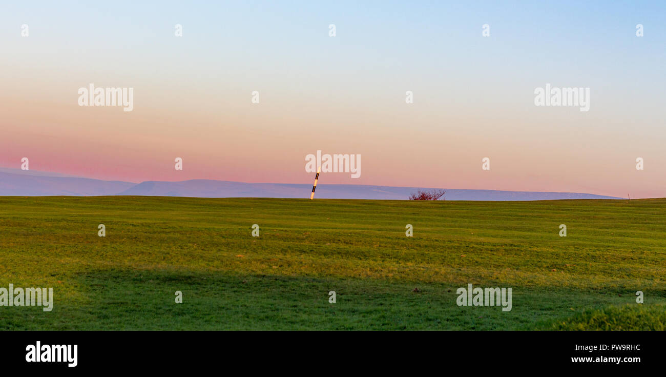 Golf course with striped pin and hills in the distance. Werneth Low ...