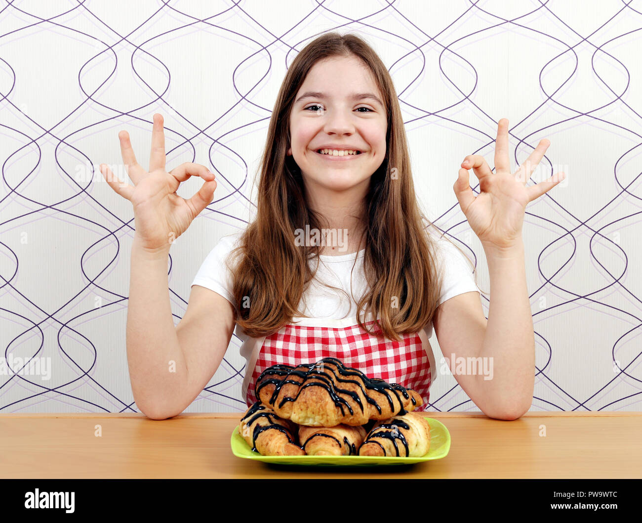 happy little girl with croissant and ok hand signs Stock Photo - Alamy