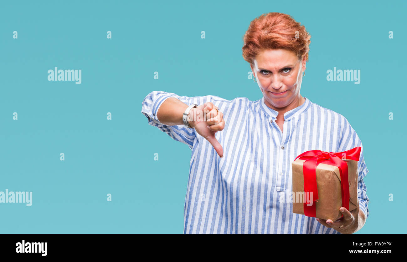Senior caucasian woman holding gift over isolated background with angry ...