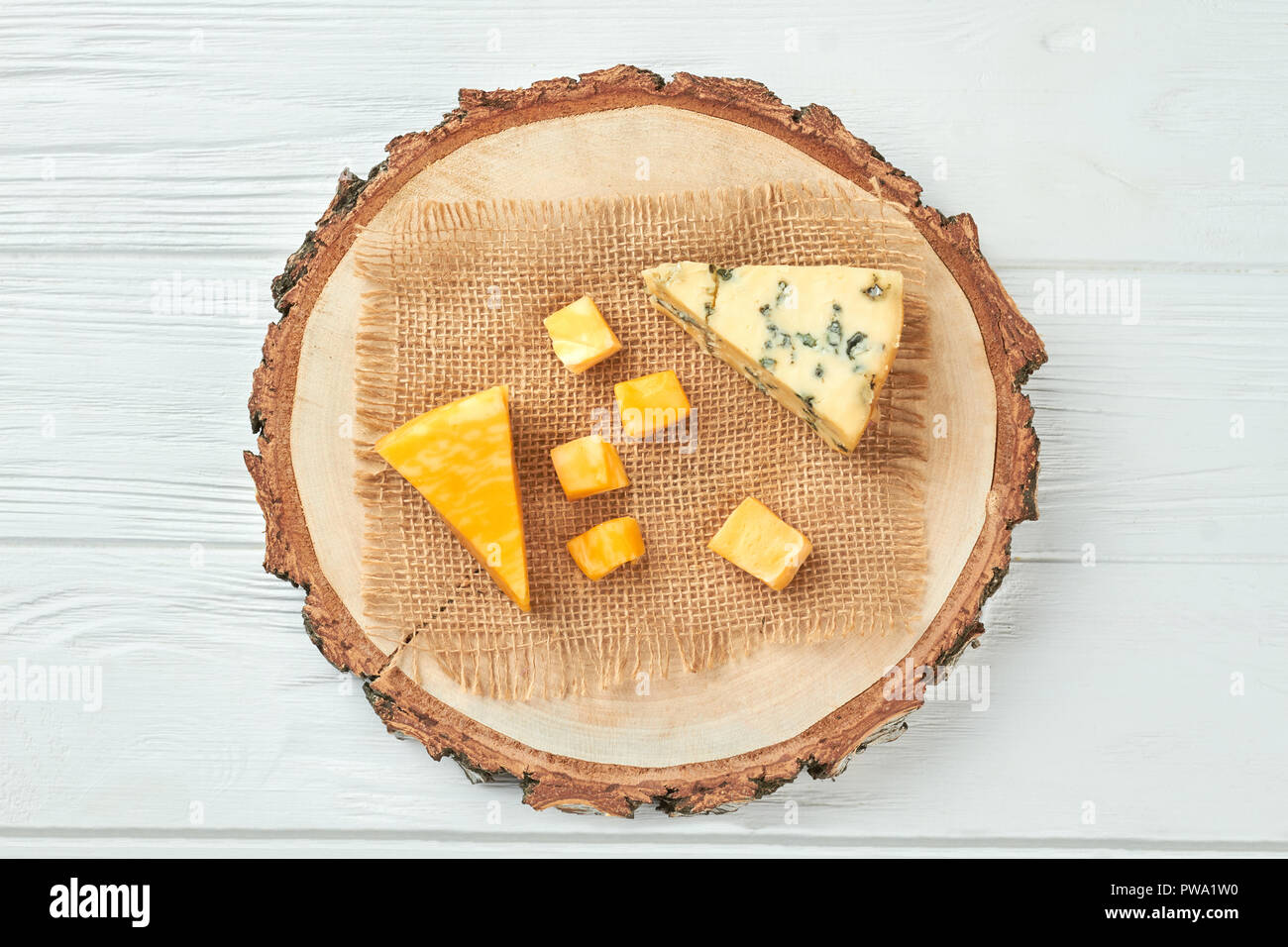 Wooden disc with different types of cheese. Cheese platter on white ...