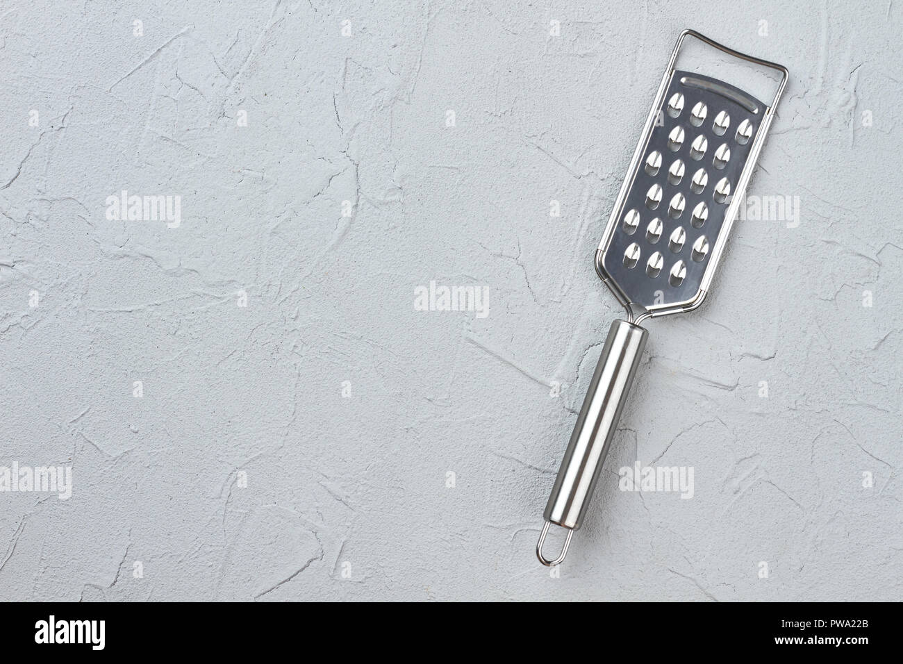 Cheese grater and copy space. Stainlees steel grater on grey textured ...