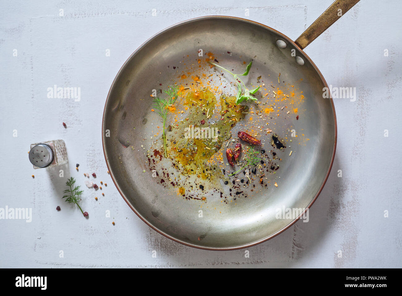Various seasoning in vintage frying pan displayed on white rustic table ...