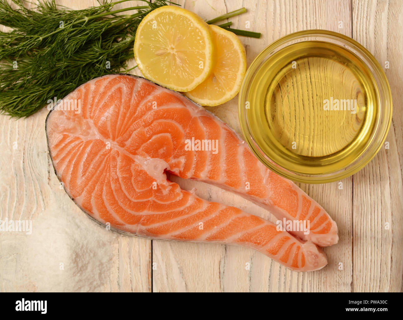 One big fresh raw salmon steak with lemon slice on the rustic table ...