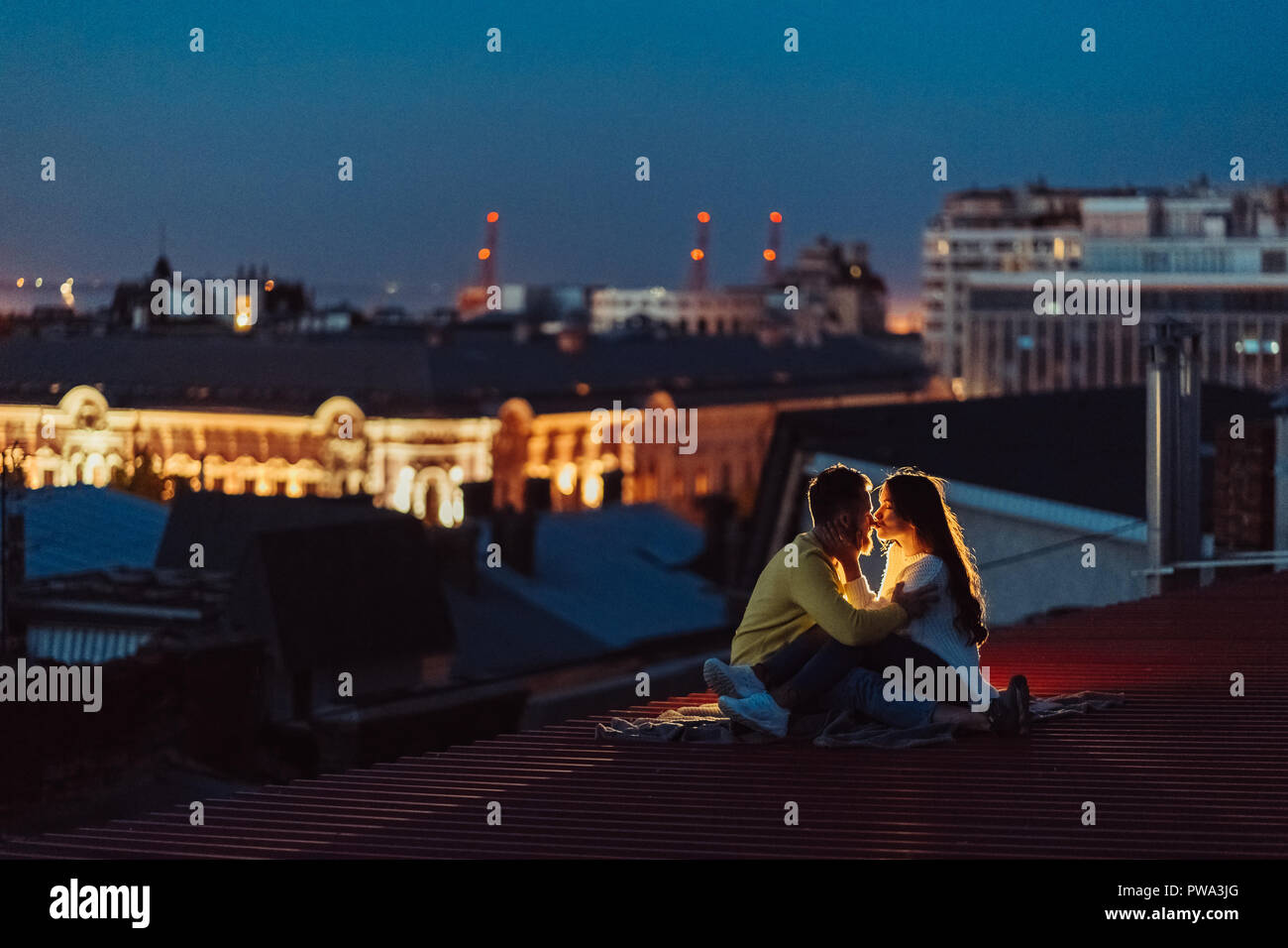 Loving couple is sitting on the roof of the house. In the distance, the ...