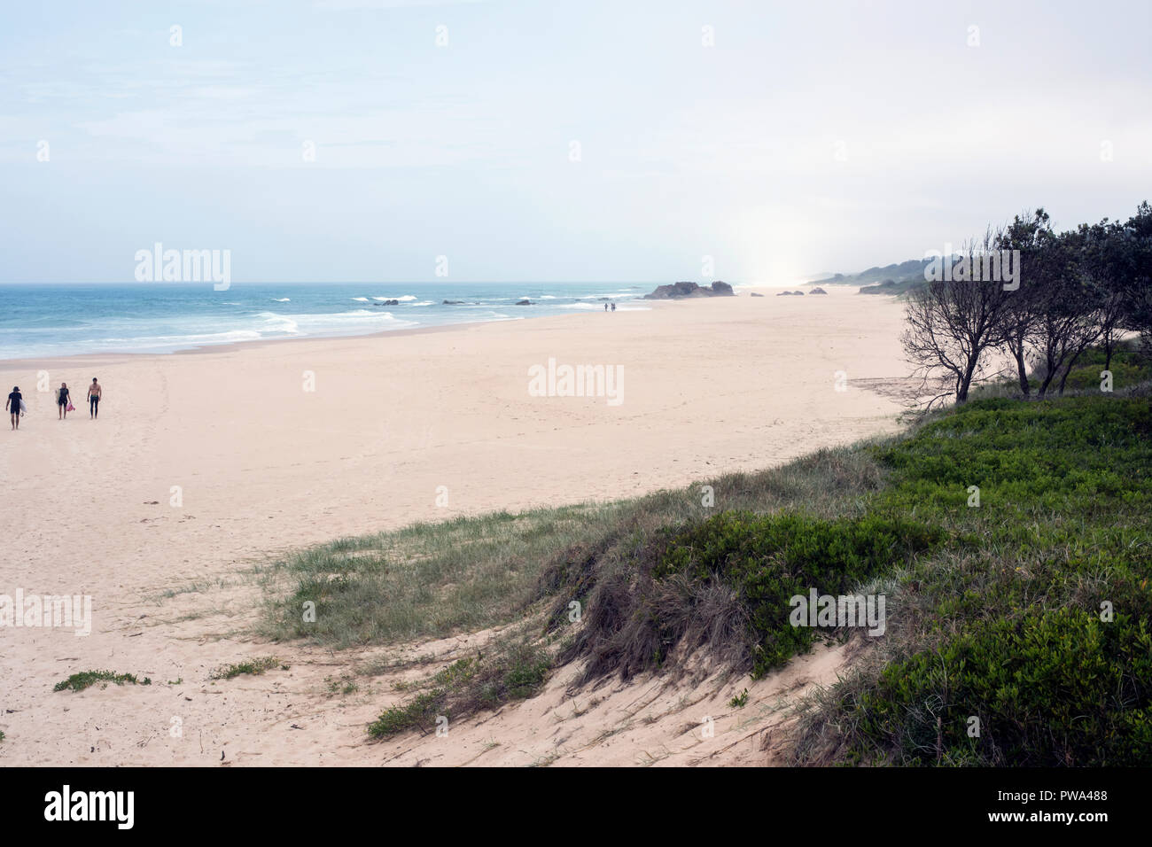 Distant figures walking along an idyllic sandy beach hi-res stock ...