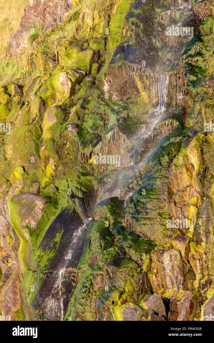 A close up of the waterfall on Tresaith beach cascading down the cliff ...