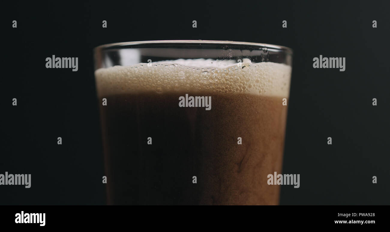 Closeup dark stout beer with bubbles over black background, wide photo ...