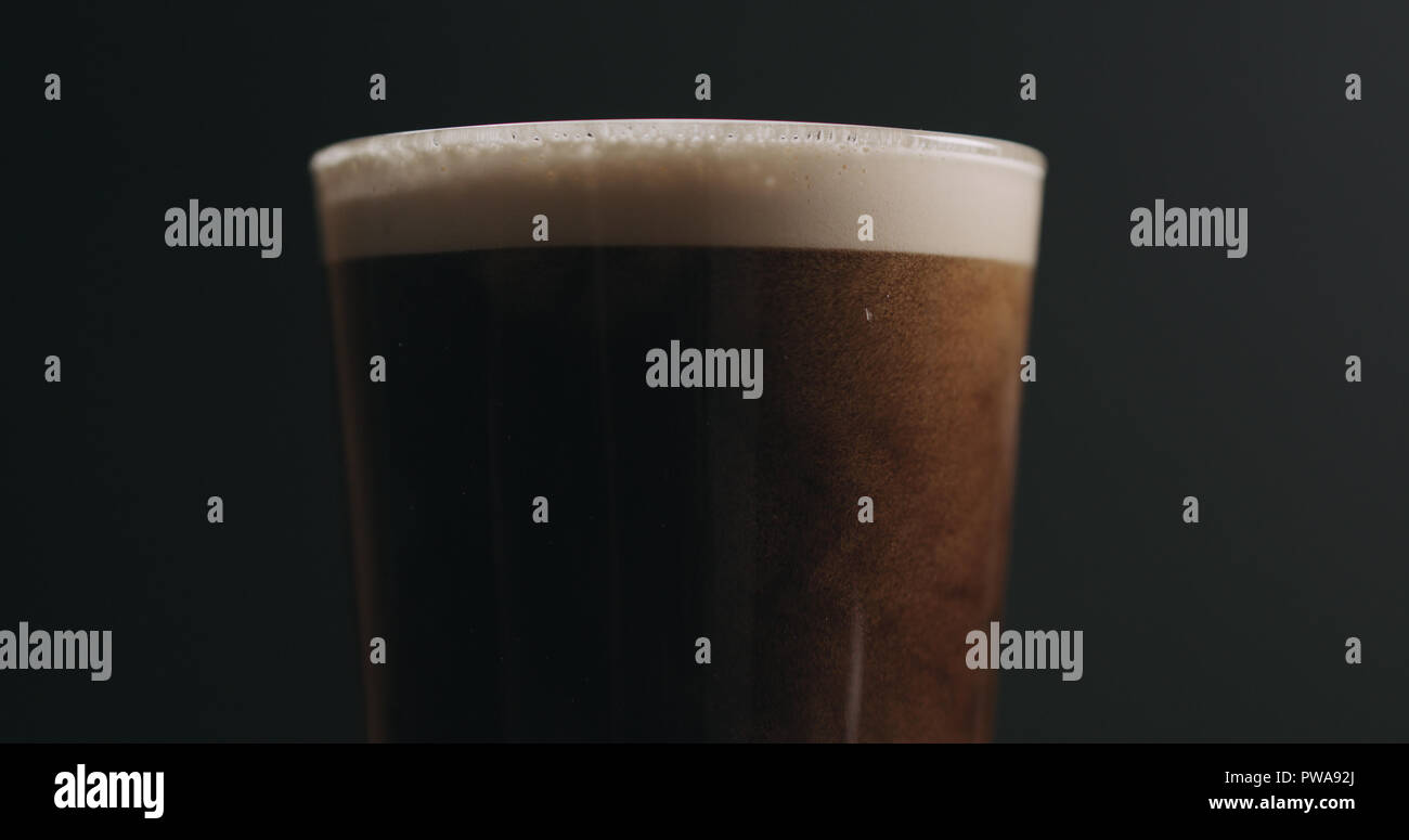 Closeup dark stout beer with bubbles over black background, wide photo ...