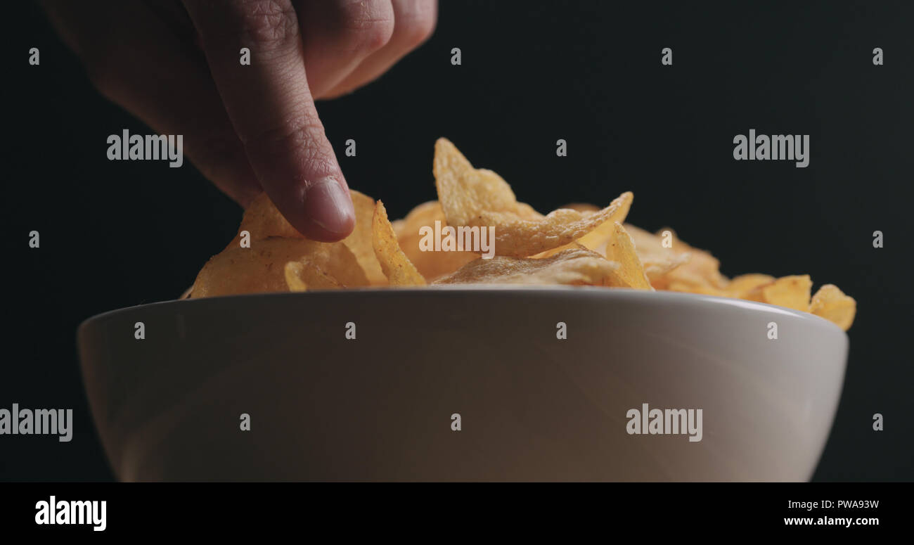 closeup man hand taking potato chip from white bowl low angle shot ...