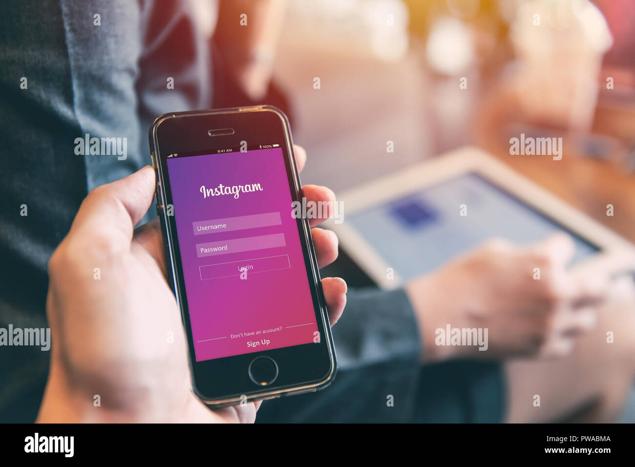 Instagram App on iPhone with people using tablet background closeup ...