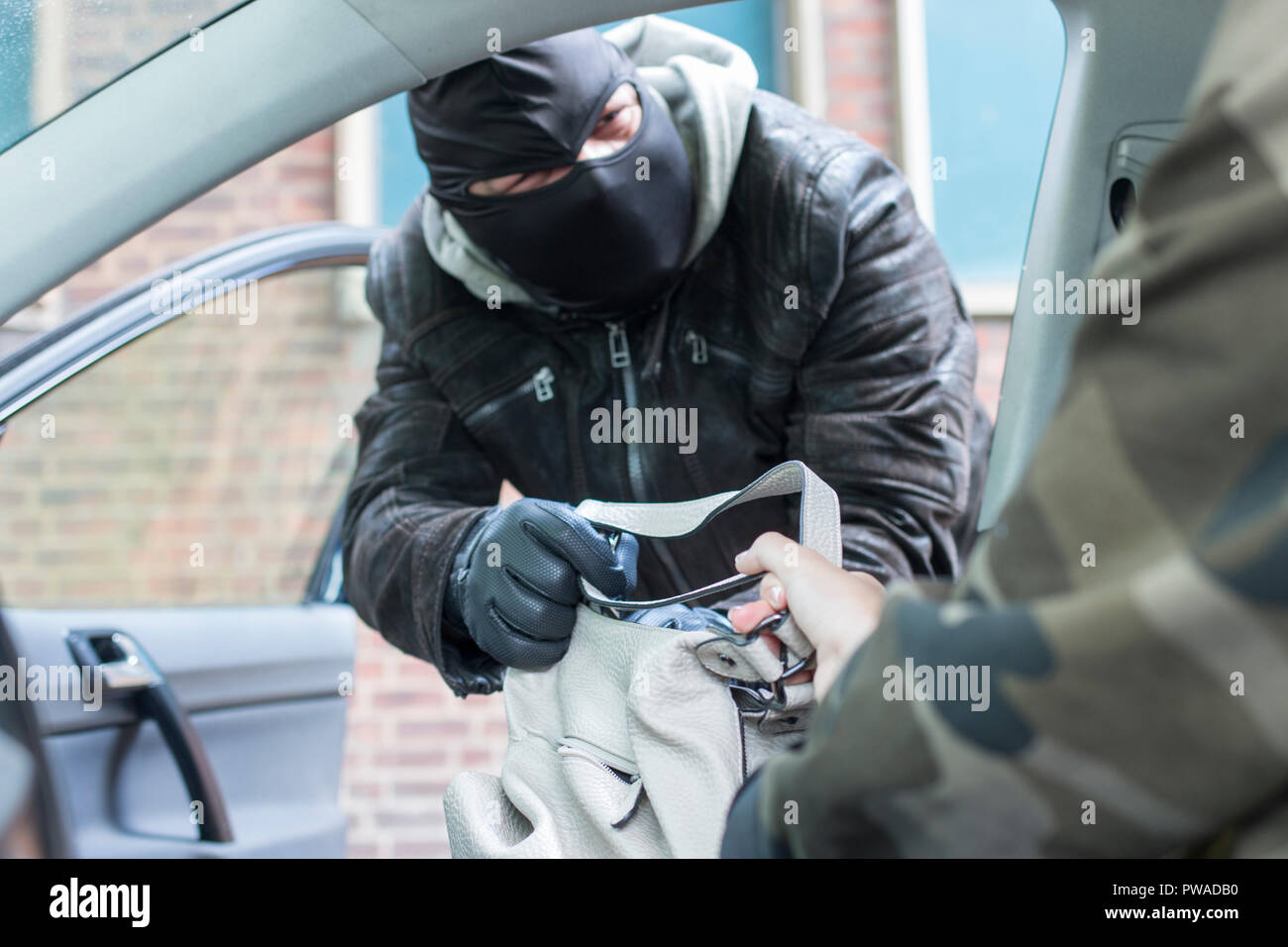 A robbery steals a handbag from a women in a car during daytime Stock ...