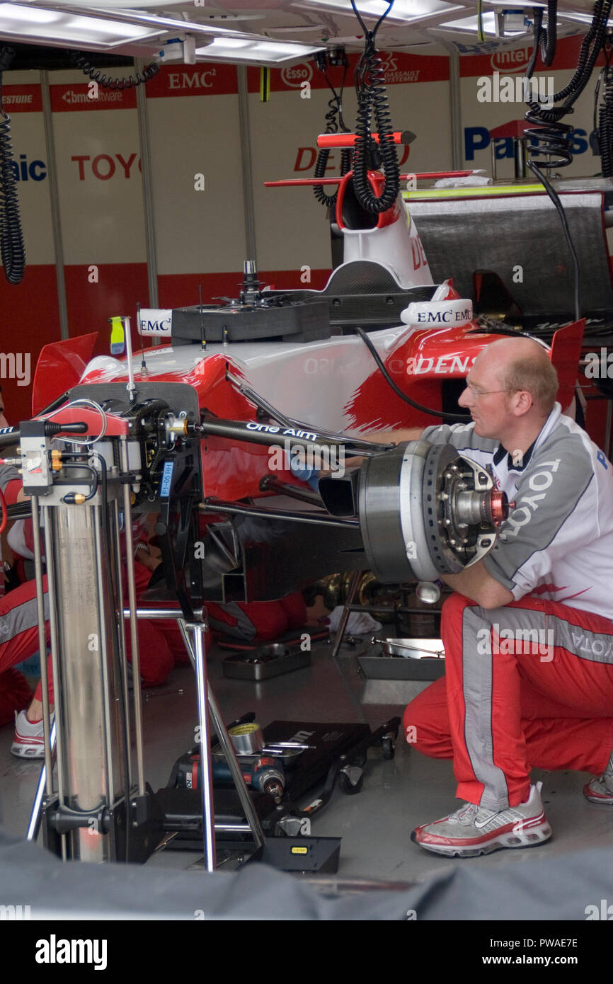 F1 mechanics at work on a Toyota F1 race car in the pit lane workshop ...