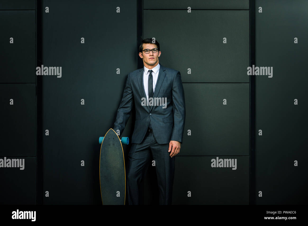 Young handsome man with business suit riding on a longboard - Corporate ...