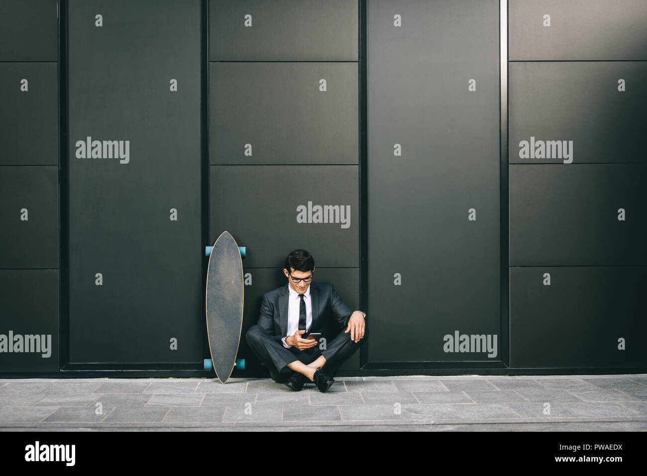 Young handsome man with business suit riding on a longboard - Corporate ...