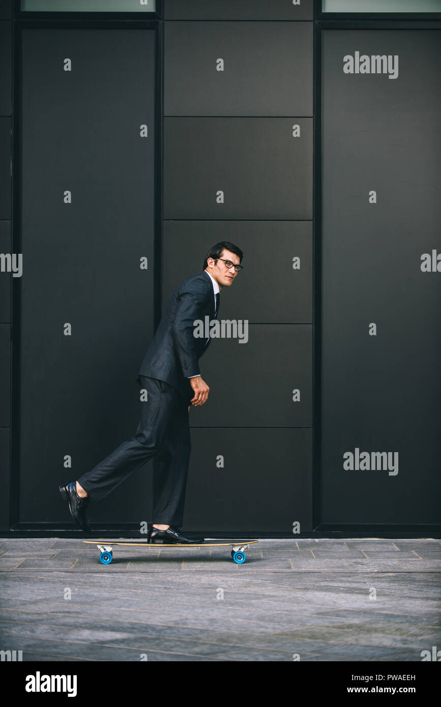Young handsome man with business suit riding on a longboard - Corporate ...