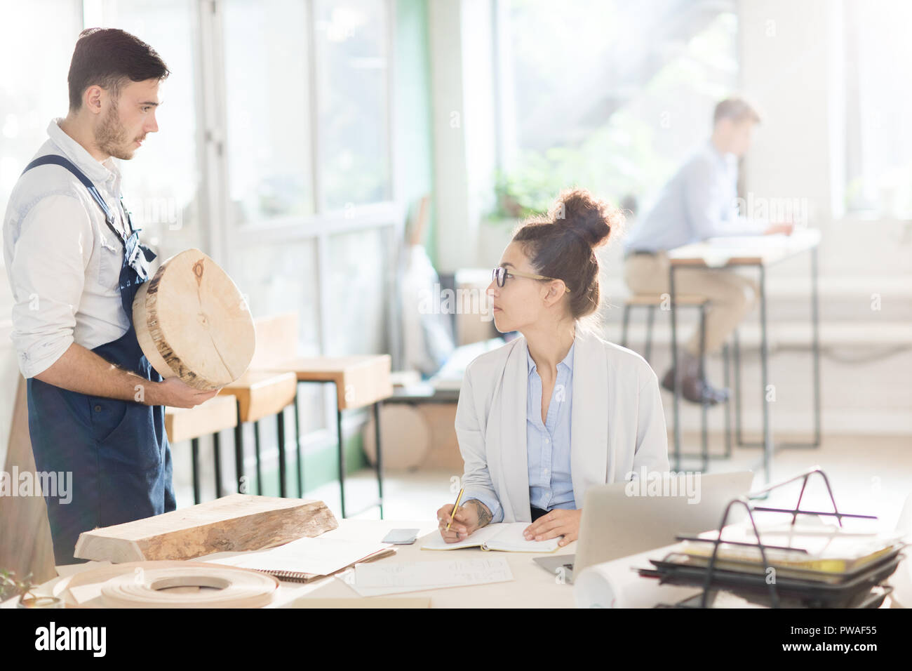 Male engineer showing expert piece of wood while discussing its ...