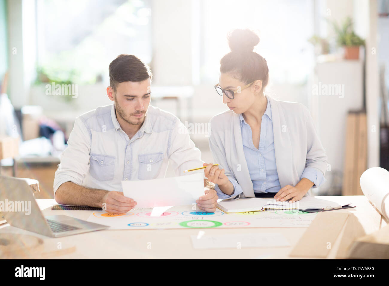 Two young professionals discussing paper and working over new business ...