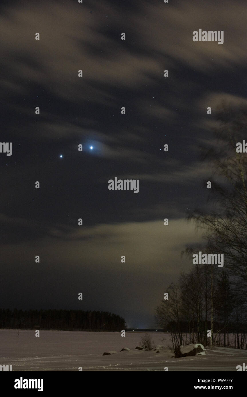 Conjuction of planets Jupiter and Venus on night sky above snowy winter ...